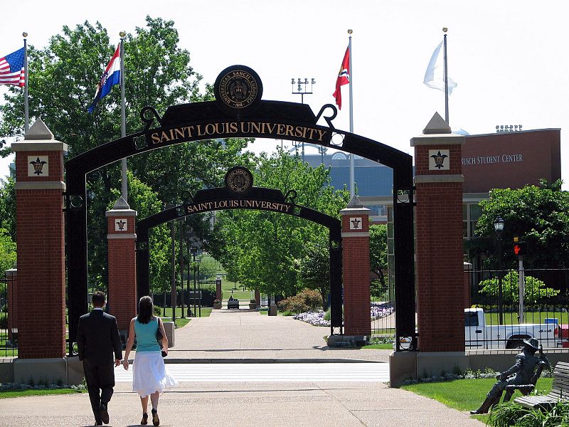 A man and woman walk past the entrance to saint louis university. – Do ...