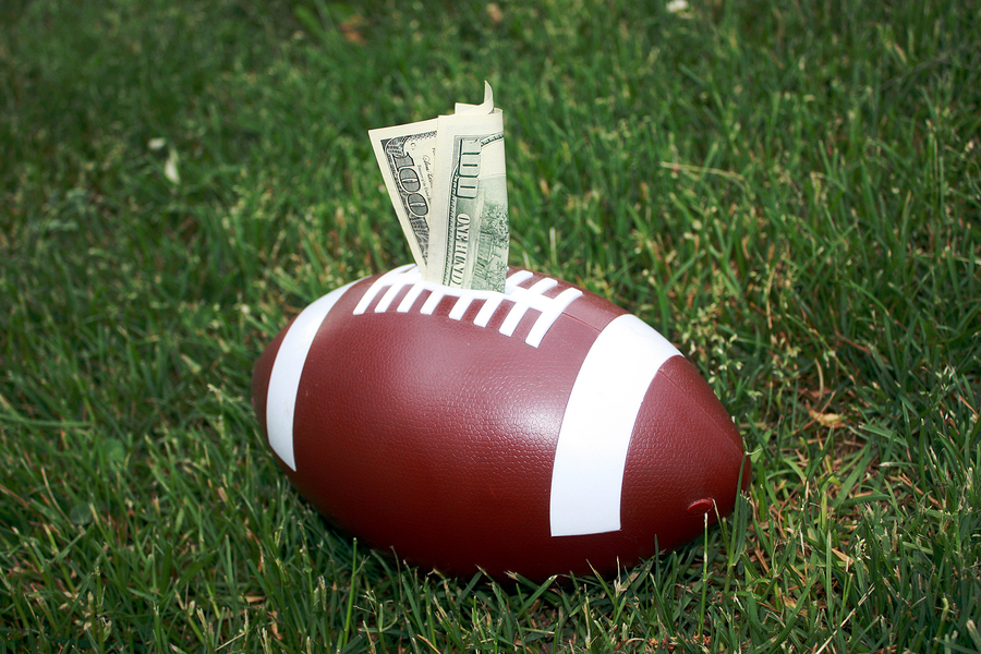 A football shaped like a dollar bill sitting on the grass. – Do It ...